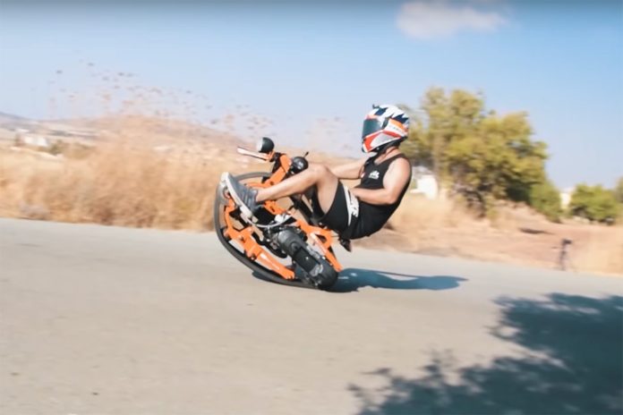 Single-wheel, recycled-tire mini motorbike leans back for wheelies