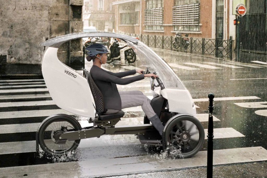 Semi-enclosed, three-wheeled, pedal-powered vehicle with electric assist