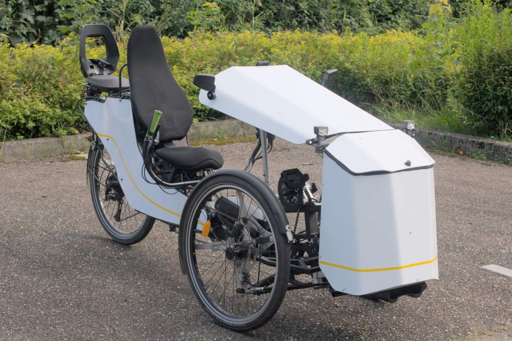Semi-enclosed recumbent e-trike is a blend of bicycle and car